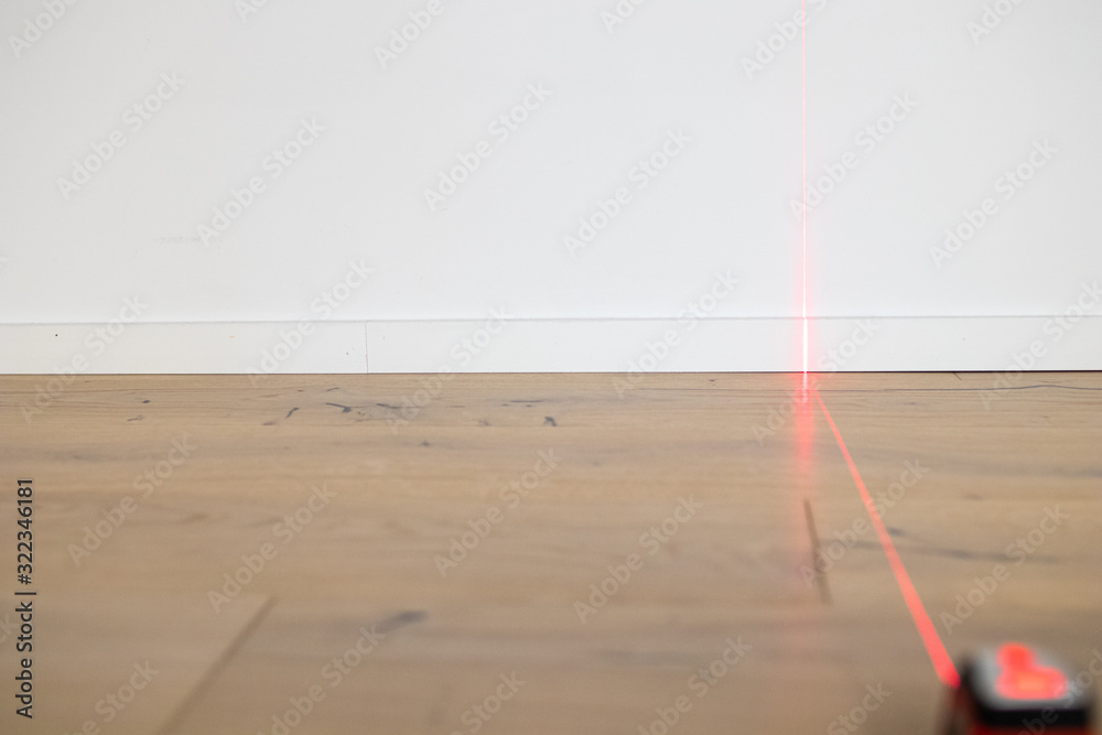 Laser meter on white wall and parquet in new apartment. Precision ...