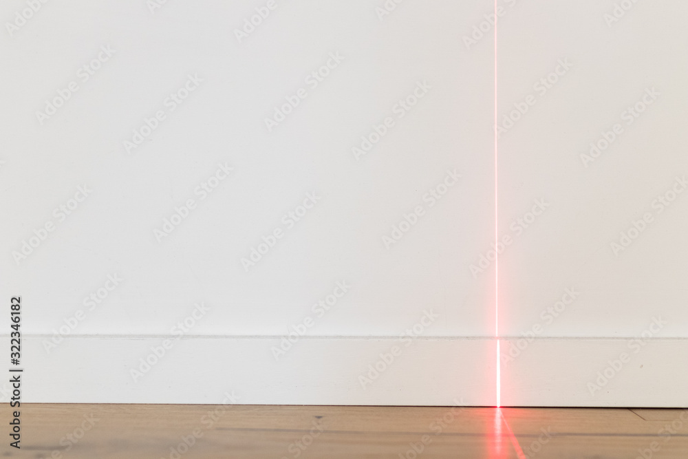 Laser meter on white wall and parquet in new apartment. Precision ...