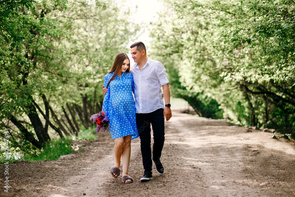 A pregnant girl and her husband are walking in the forest, a ...