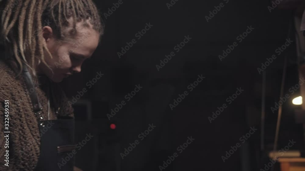 A modern woman tanner with dreadlocks makes a leather product. She ...