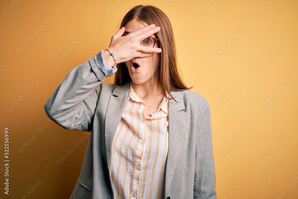 Young beautiful redhead woman wearing jacket and glasses over isolated ...
