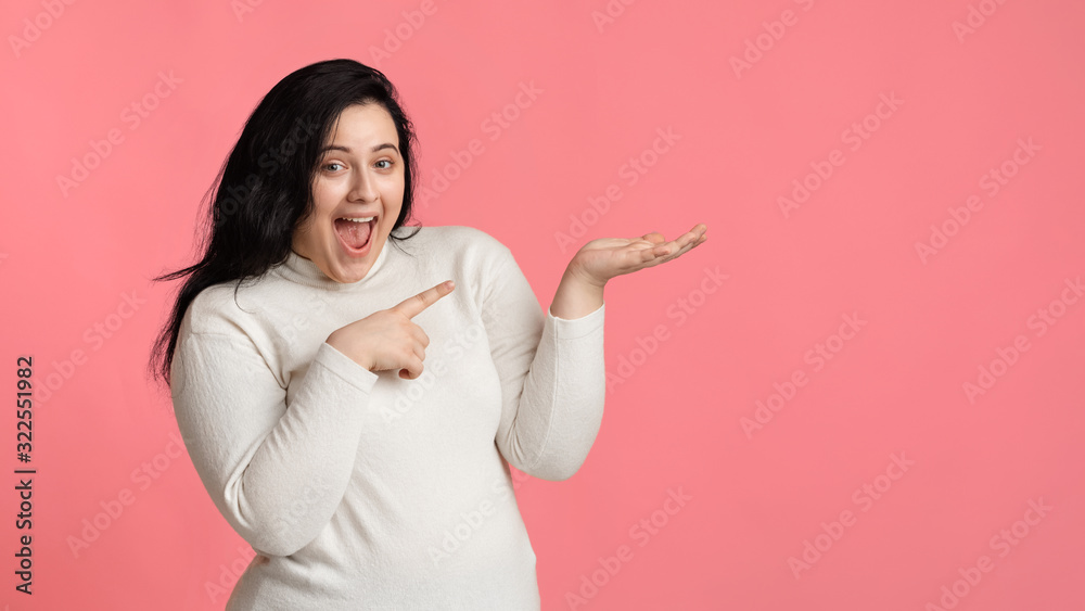 Overjoyed plump woman pointing finger at open palm, demonstrating ...