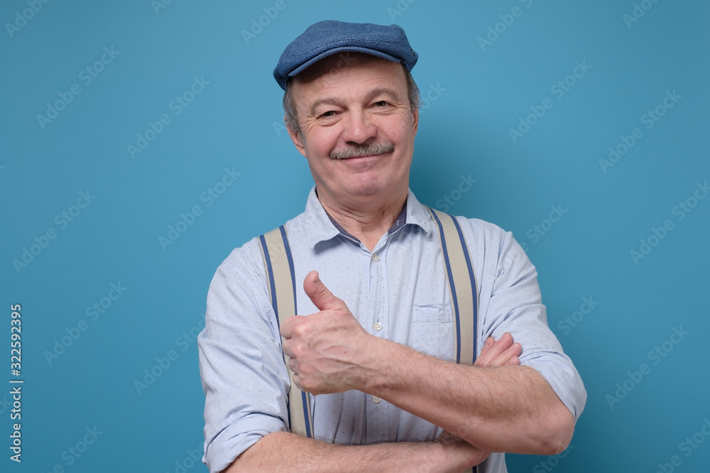 Portrait of friendly confident senior man in summer hat showing thumb ...