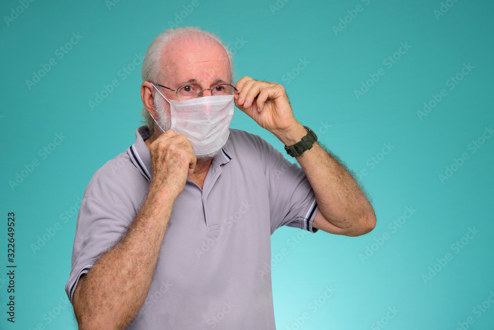 Old Man with face mask against virus on a green background, elderly man ...