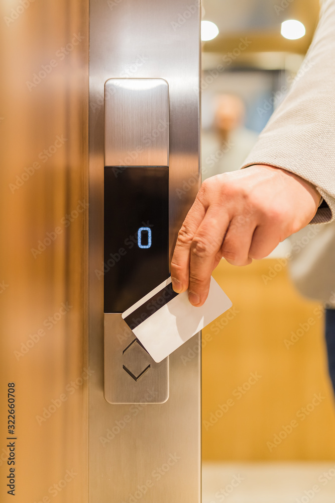 Man holding key card on sensor to open elevator door in modern building ...