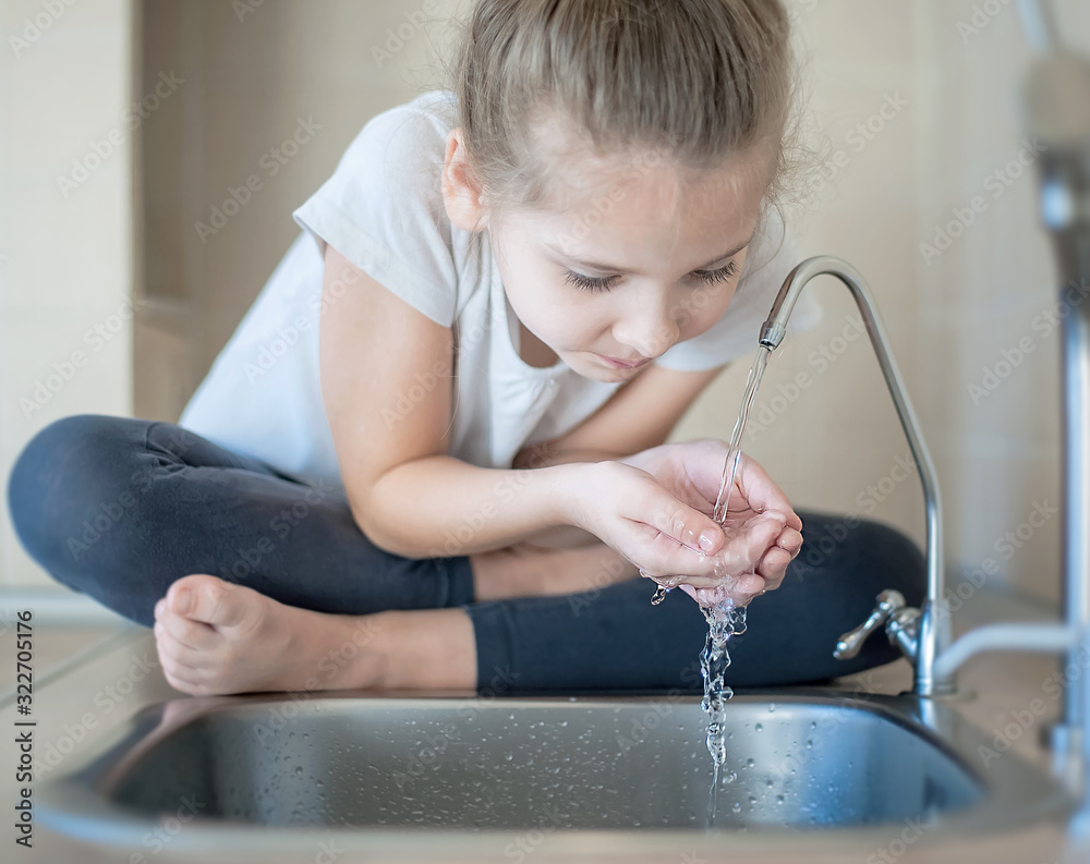 Caucasian little girl drinking fresh water in kitchen at home. Thirsty baby. Hands open for ...