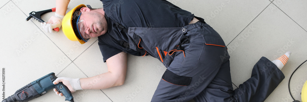 Portrait of injured construction worker laying on floor after fall ...