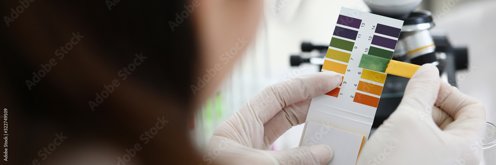 Female chemist holding litmus paper in hands. Analyzes ph test in a ...