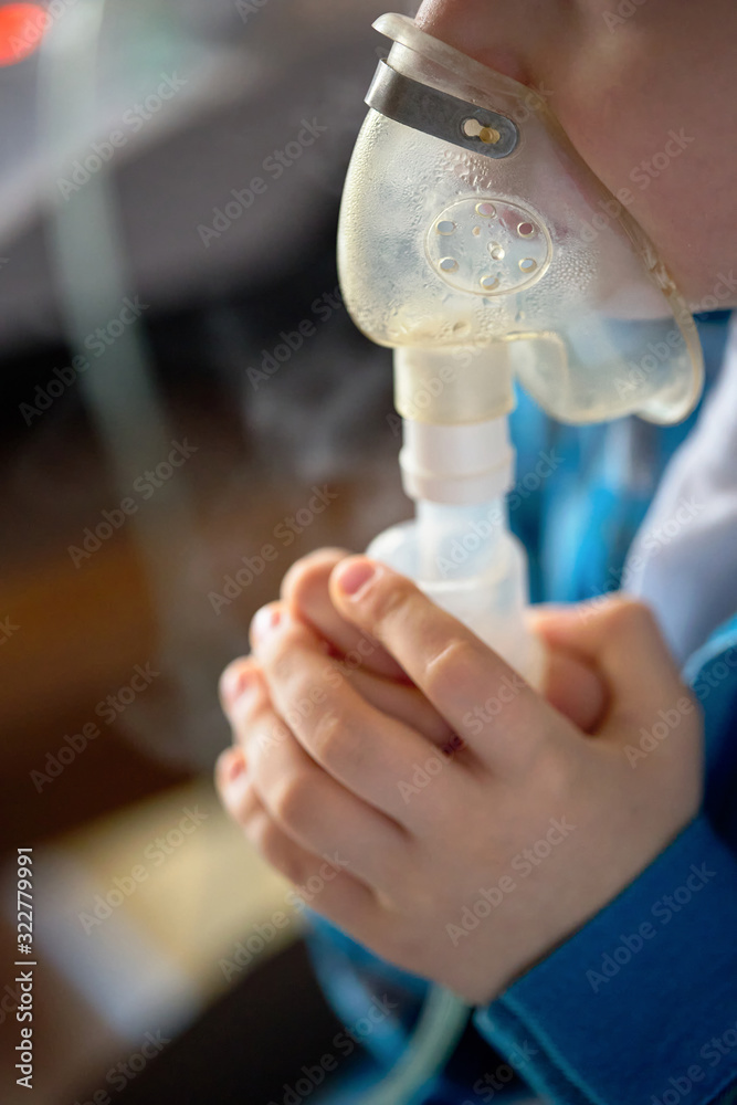 Child makes inhalation at home with nebulizer steam on out of focus ...