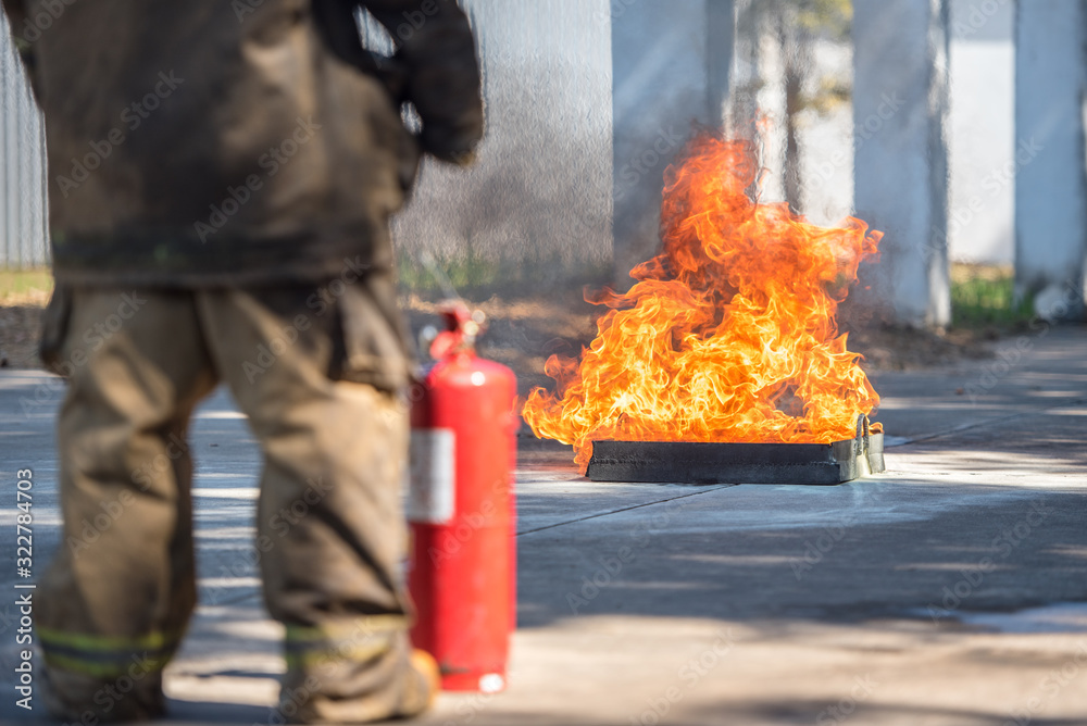Fireman showing use a fire extinguisher on a training fire hydrant with ...