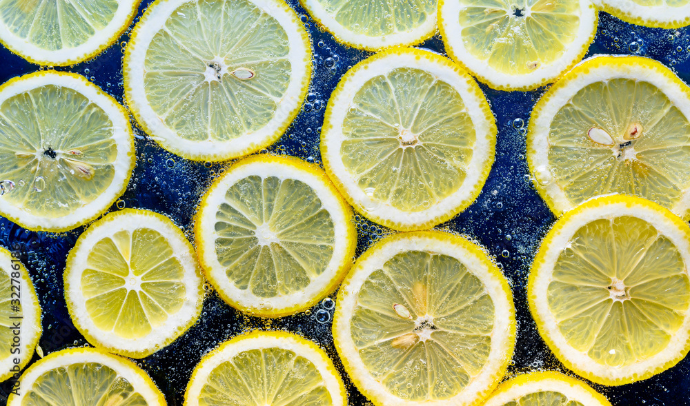 Lemon Slices in the water with air bubbles on dark blue background ...