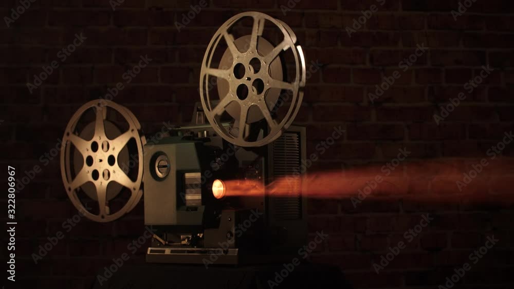 Wide shot of a home movies projector playing in the dark with ...