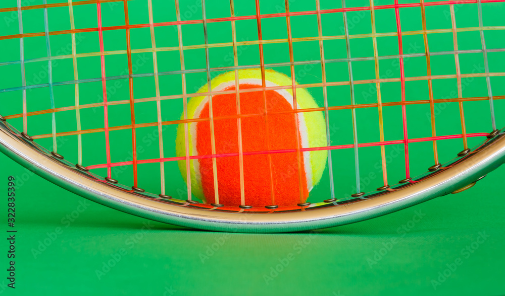 a racket and a tennis ball/ the oval of a tennis racket metal with ...