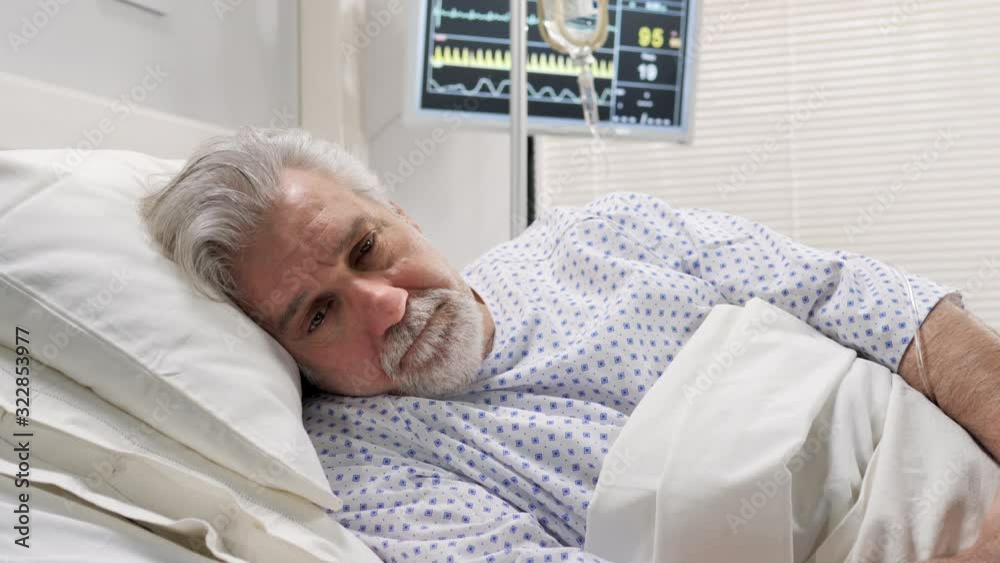 sad suffering old male patient lying in the hospital bed staring into ...