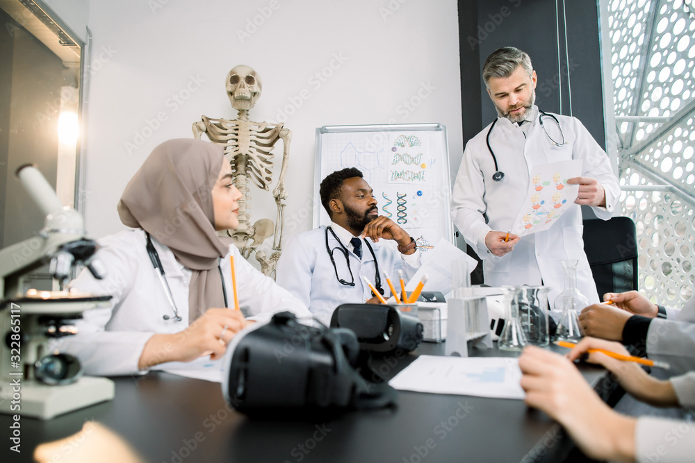 Group of multiracial medical students sitting together and studying ...