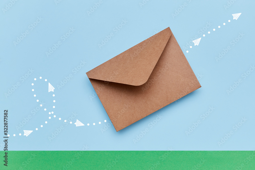 Craft brown envelope flying above green paper ground with indicated ...