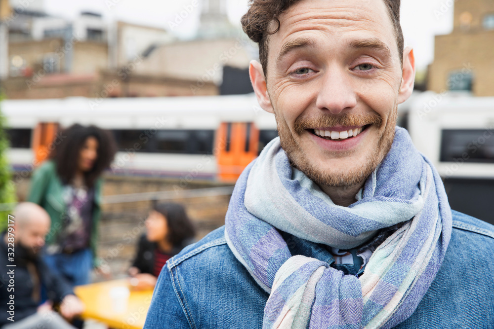 Portrait of man with group of friends working on tablets at outdoor ...