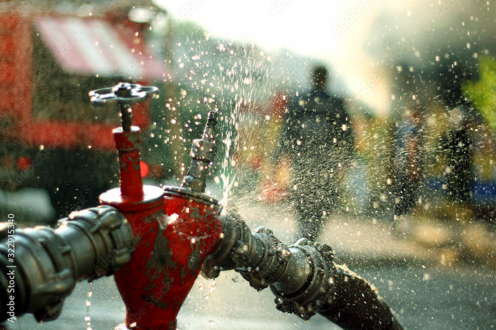 Water splashes from the fire hose and hydrant connections. Firefighters ...