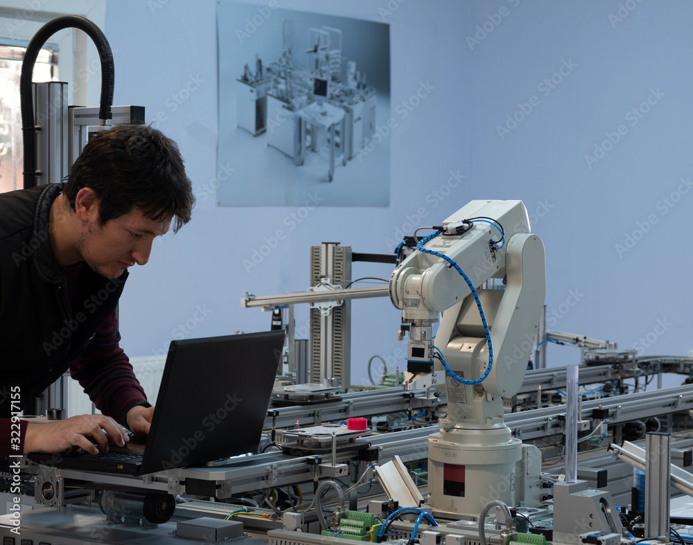 Close-up of Robot arm. Engineer is working on laptop to programming robot arm and automated car ...