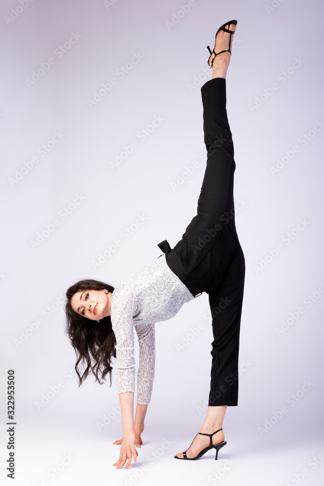 Foto de Beautiful woman gymnast in a in a shiny top, trousers and high ...