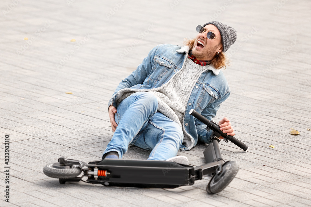 Young man fallen off his kick scooter outdoors Stock Photo | Adobe Stock