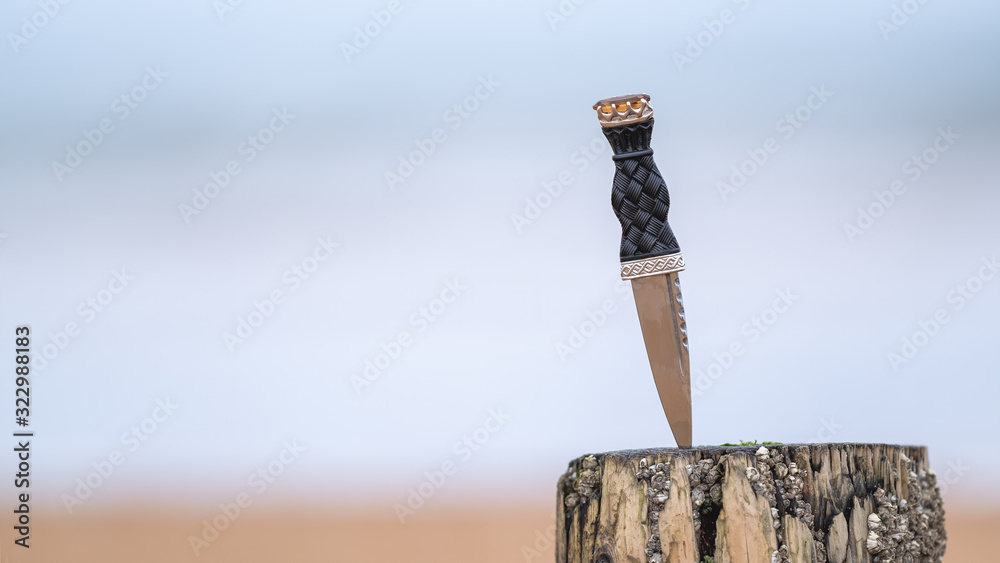 Sgian Dubh Scottish dagger stuck in a barnacle encrusted wooden pole ...