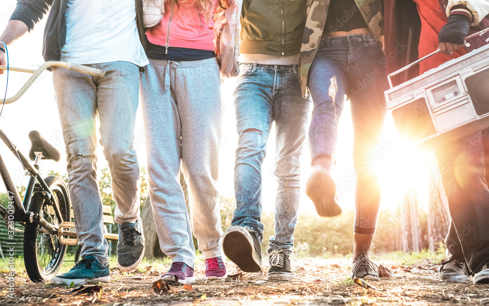 Friends walking in city park with backlight and sunflare halo ...