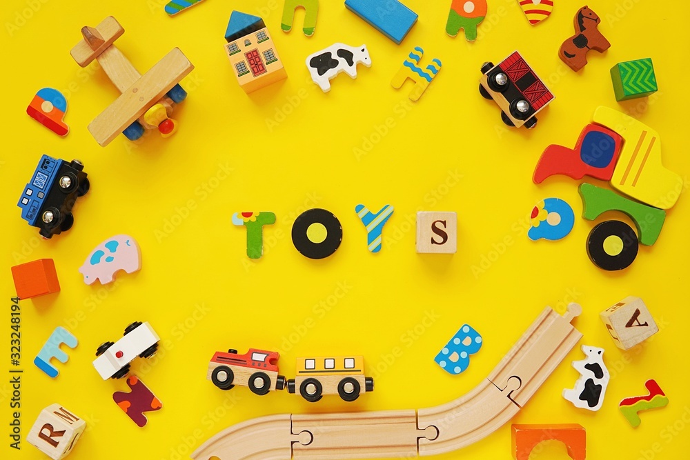 Word TOYS and frame with colorful wooden kids toys on yellow background ...