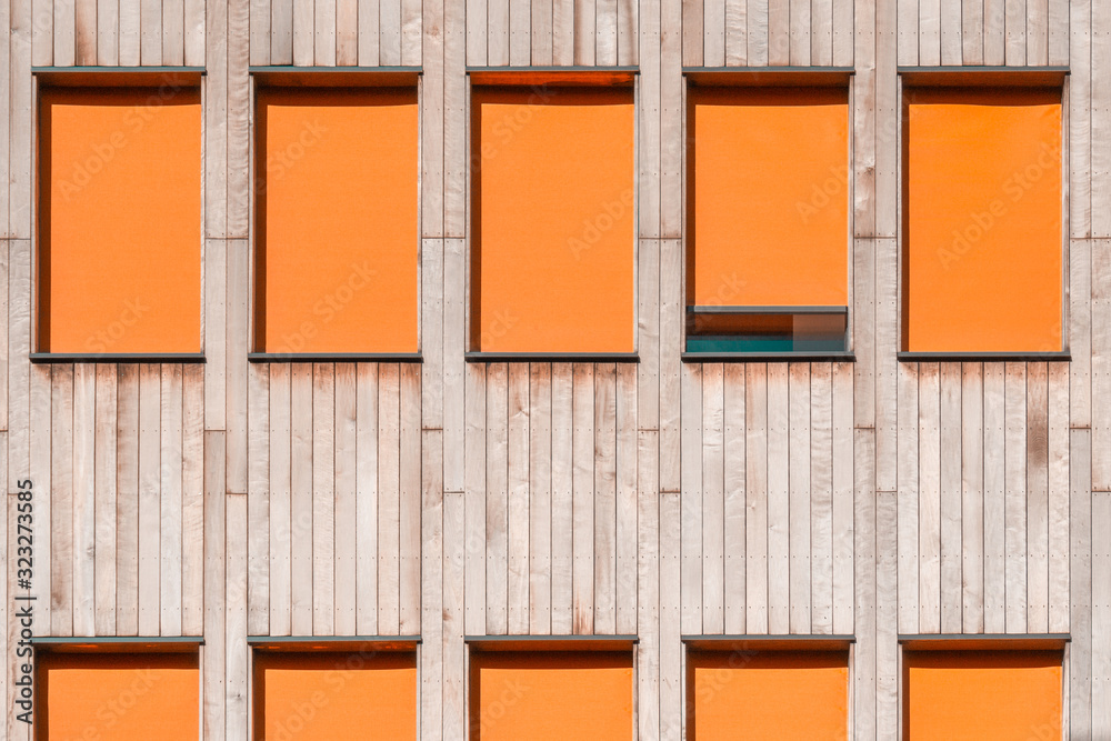 Vertical wood cladding exterior with bright orange roller blinds ...