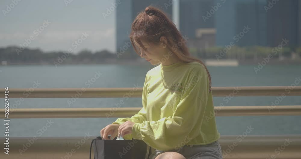 Asian Chinese girl in public area taking a surgical face mask from her ...