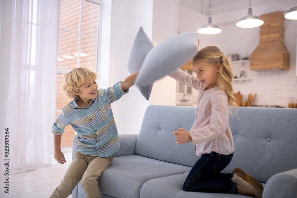 Two kids beating each other with pillows Photos | Adobe Stock
