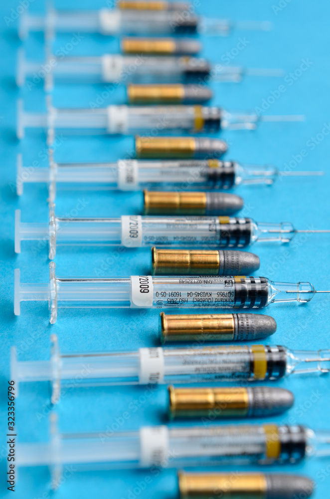 Row of hypodermic syringes and bullets on a blue background Stock Photo ...