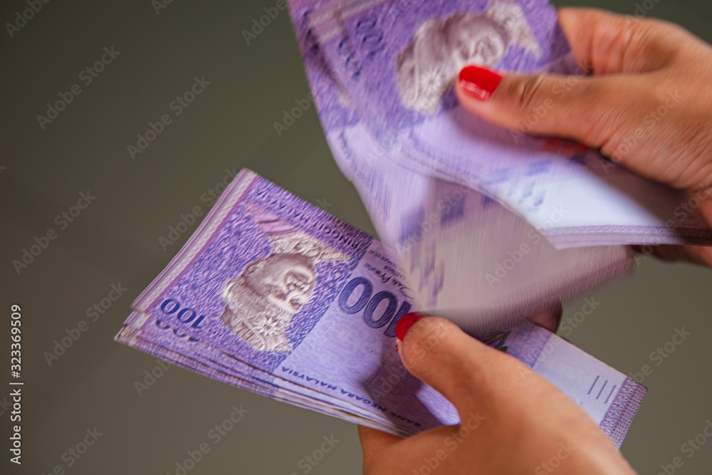 Female Hands with red nails counting 100 Ringgit banknotes. Ringgit the ...