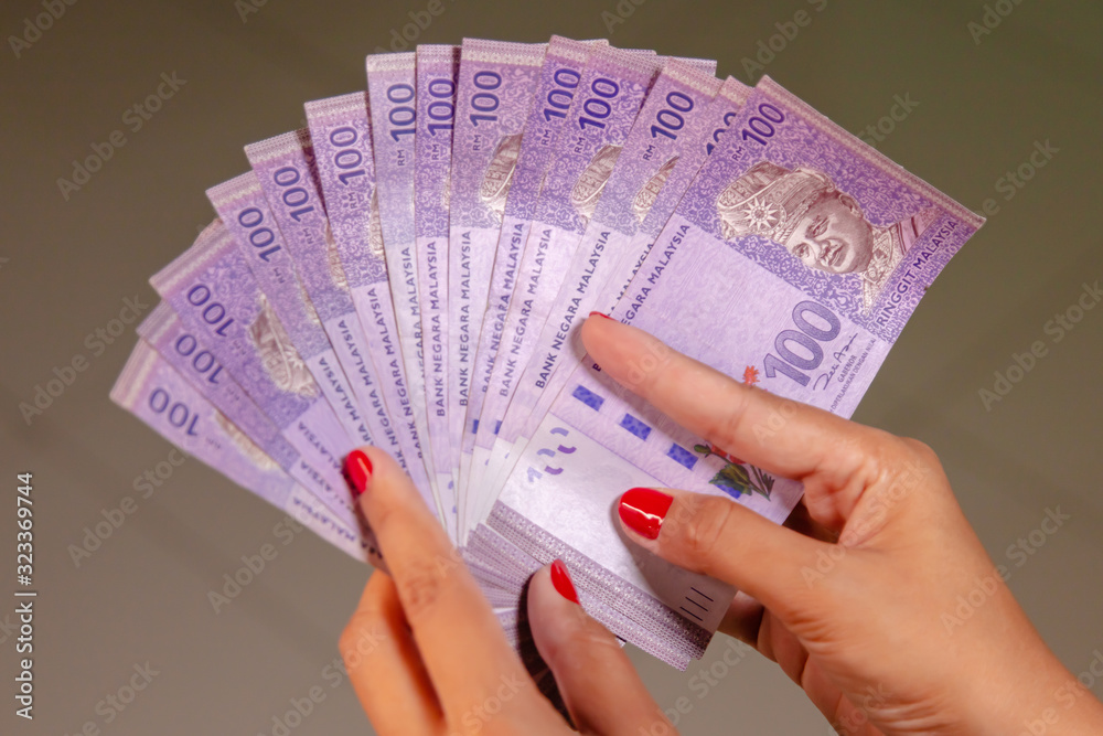 Female Hands with red nails counting 100 Ringgit banknotes. Ringgit the ...