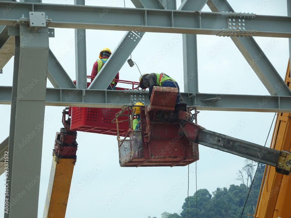 Construction workers standing in the mobile crane bucket while working ...