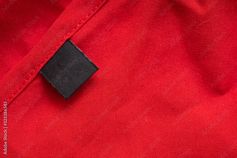 Blank black laundry care clothing label on red color fabric texture ...