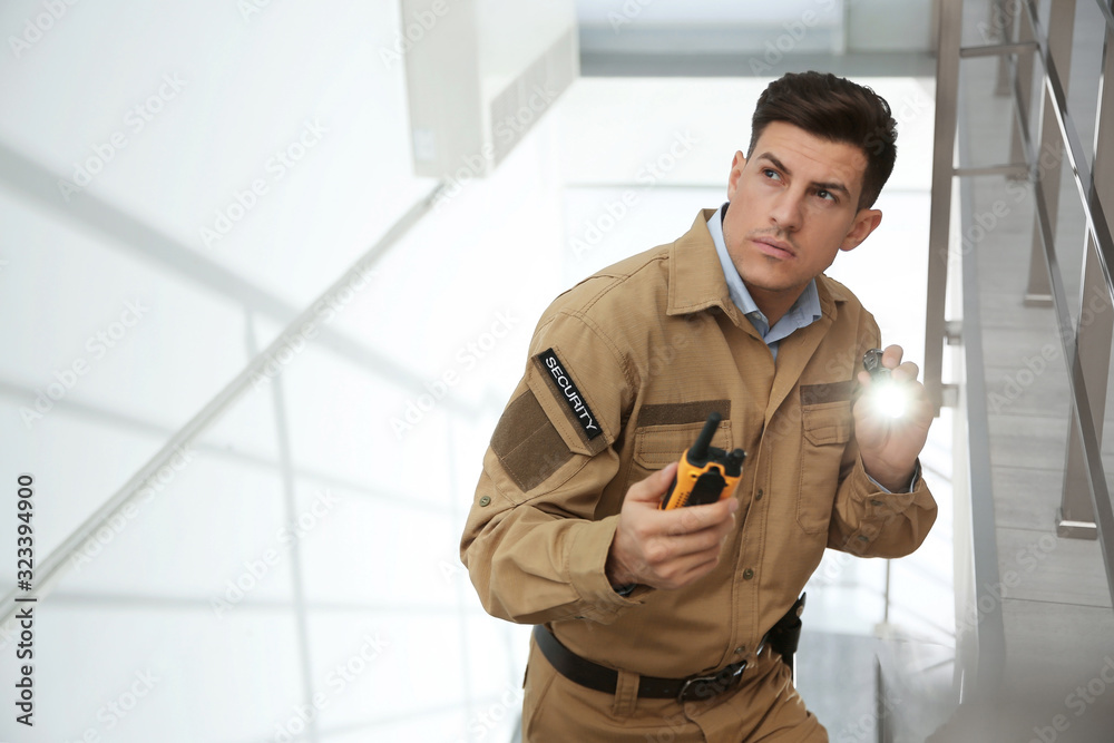 Professional security guard with portable radio set and flashlight on ...