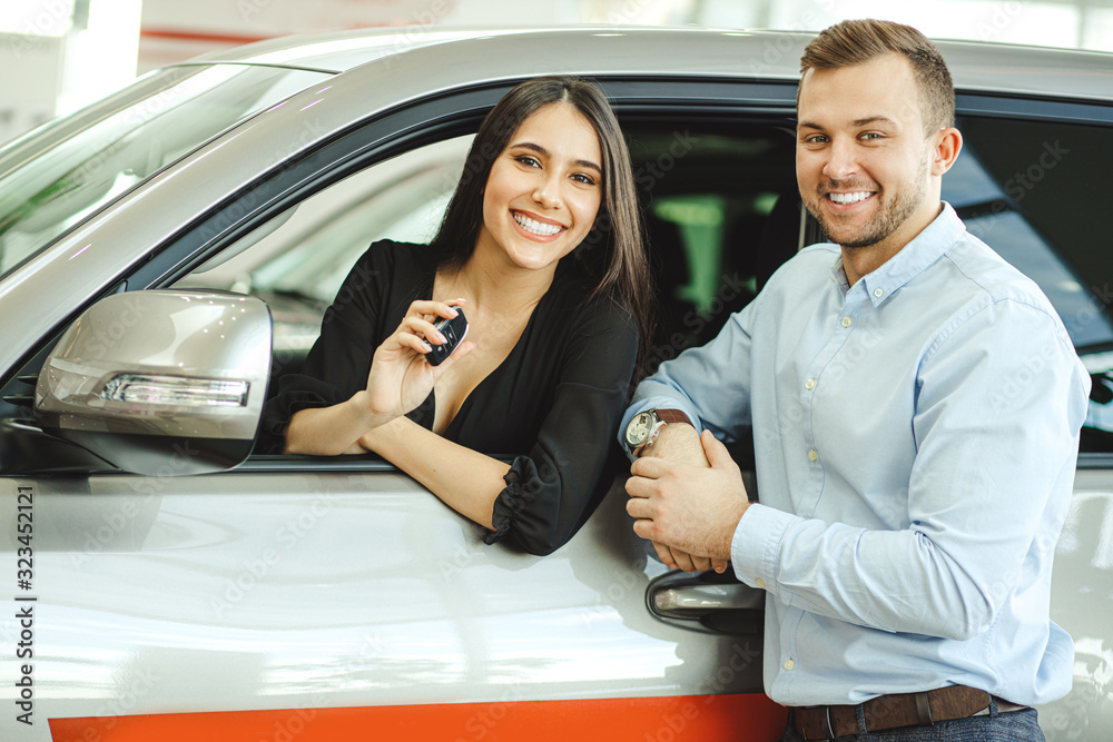 new owners of automobile, caucasian married couple posing in dealership ...