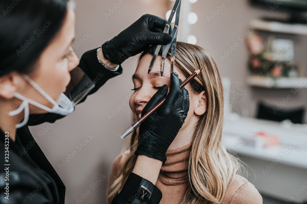 Cosmetologist measures the proportions of the eyebrows with the ruler ...