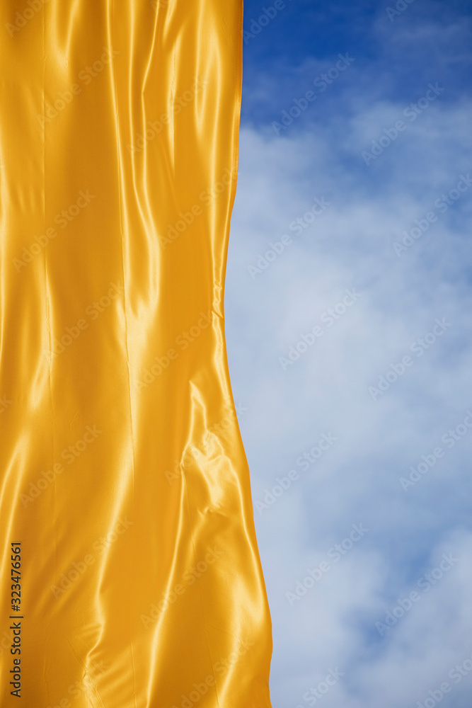 Foto de Drapeau jaune éclairé par le soleil flottant au vent sur fond ...