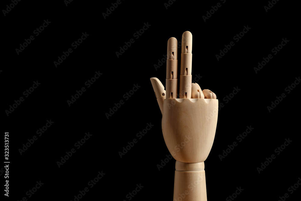 Wooden hand of mannequin for drawing shows two fingers on a black ...