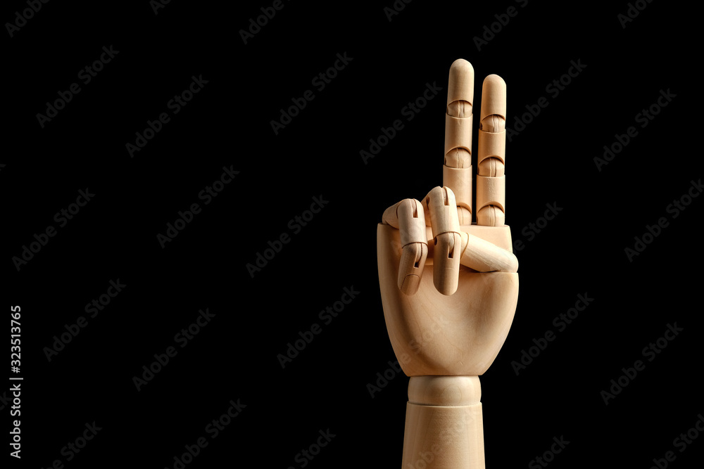 Wooden hand of mannequin for drawing shows two fingers on a black ...