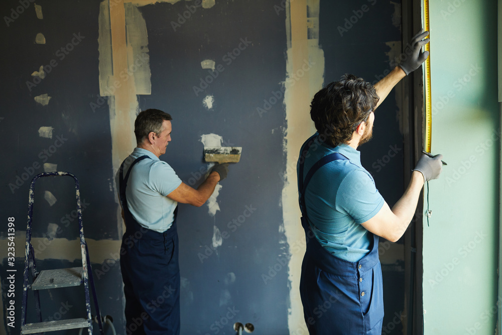 Back view of construction crew working in room while building or ...
