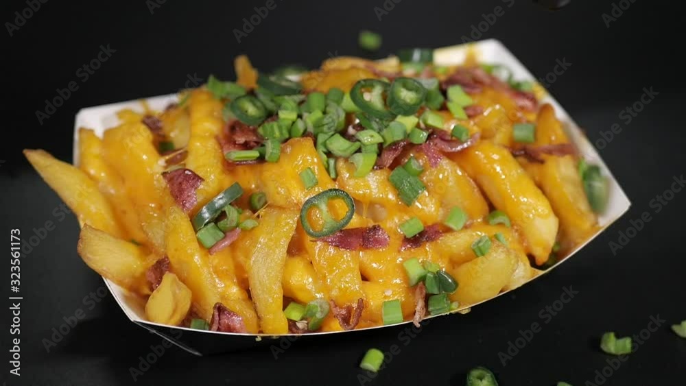 Slow Motion dropping jalapeño on hot golden french fries with fresh ...