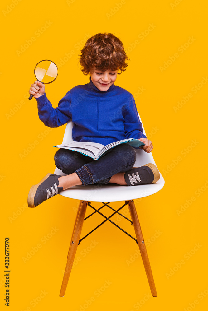 Smart boy reading book with magnifier Stock Photo | Adobe Stock