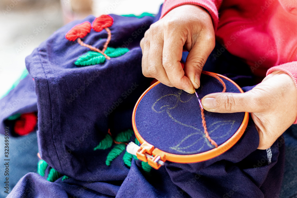 Asian woman's hand is embroidered with tribal native fabric. Sewing ...