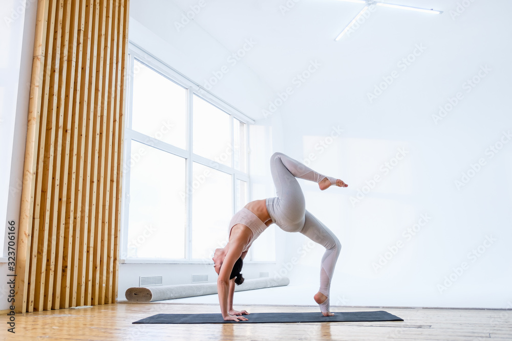Young caucasian female athlete doing bridge exercise one legged wheel ...