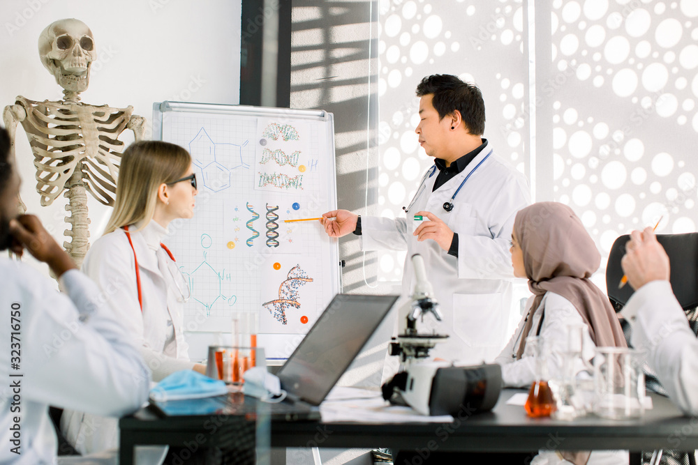 Handsome young Asian Korean male doctor standing near the clipboard and ...