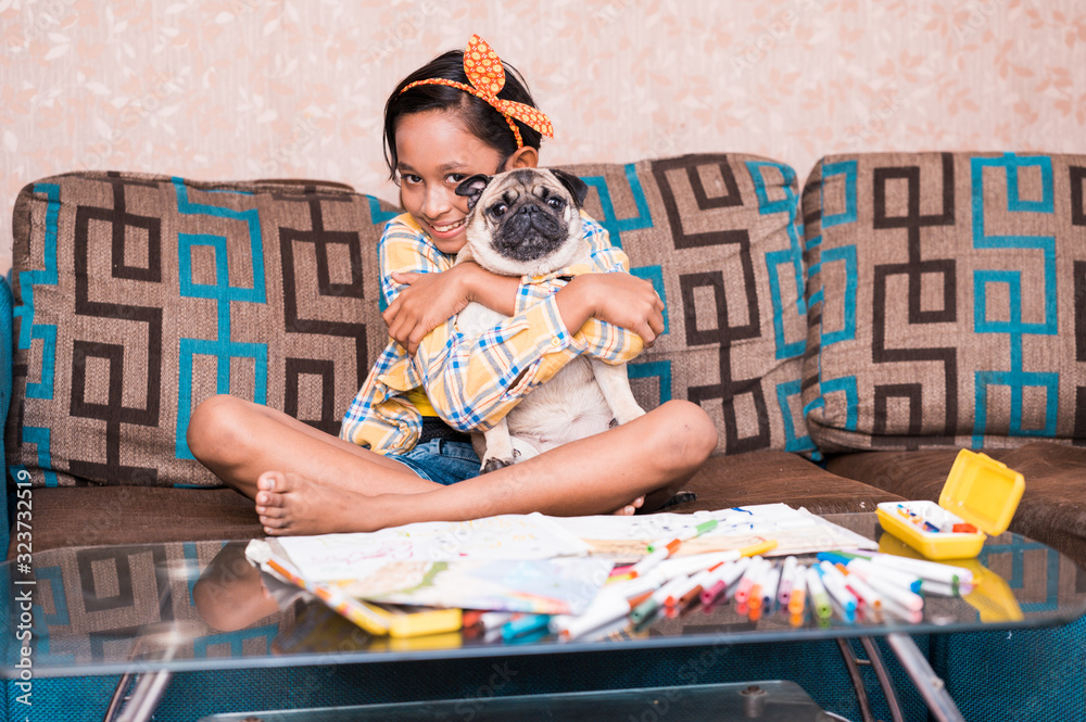 Happy child with her pet dog pug drawing on table with scatch pen ...