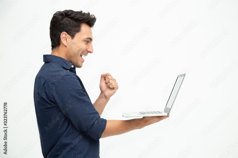 Portrait of an excited man holding laptop computer and celebrating ...